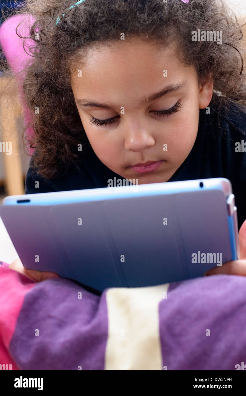 Young Little Girl Is using Ipad While Lying on the Sofa Stock Photo - Alamy
