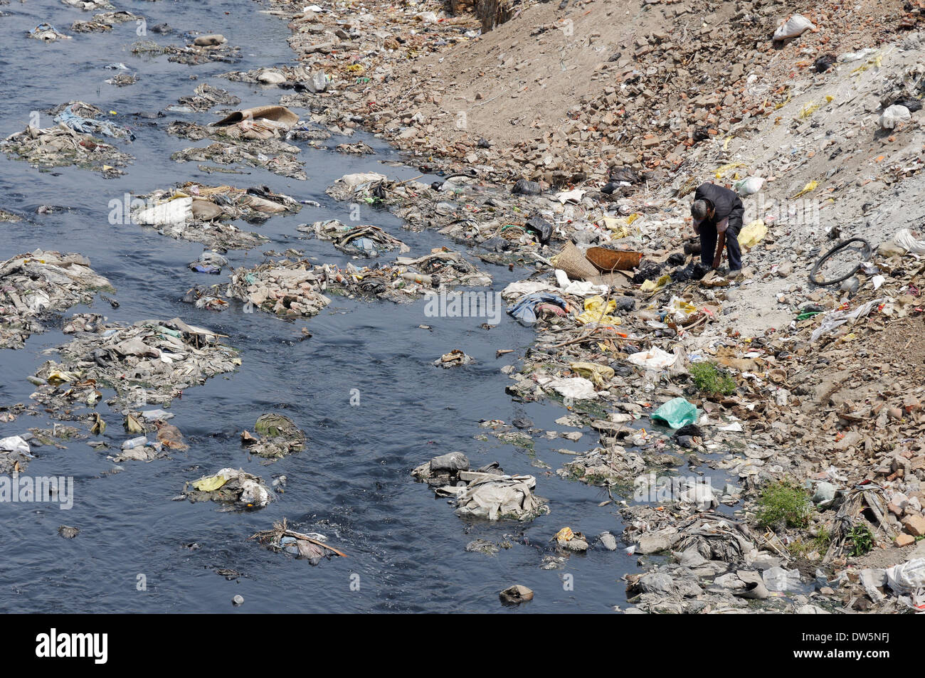 A man sifting through rubbish in the filthy river Bagmati in Kathmandu ...