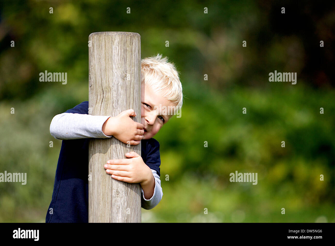 Happy child hiding behind wooden post Stock Photo - Alamy