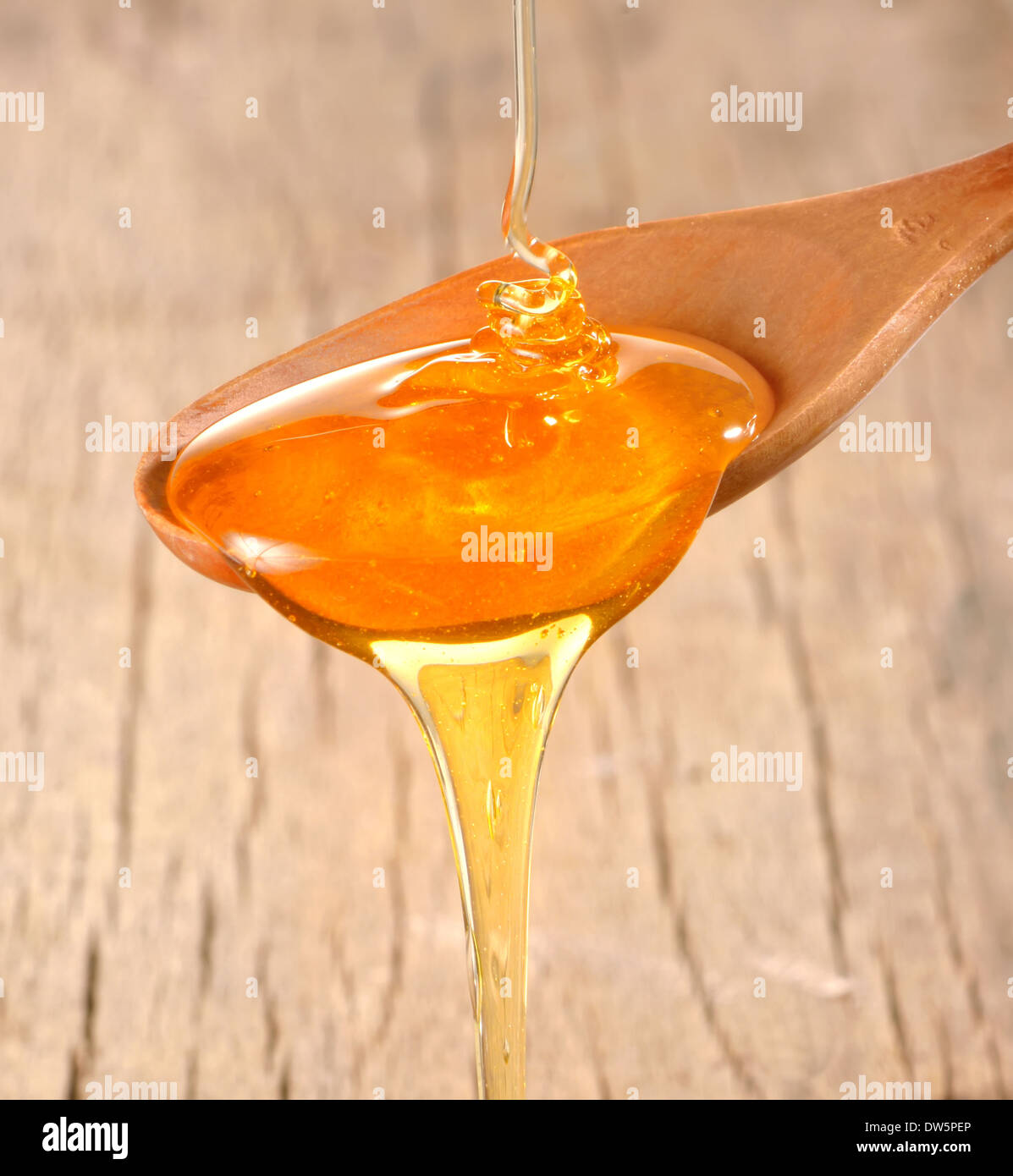 Honey dripping from a wooden spoon Stock Photo - Alamy