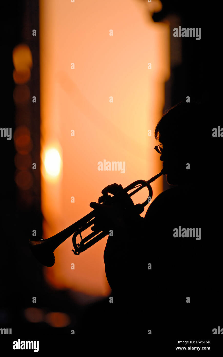 Street musician playing the trumpet in the shadows of the City Hall ...