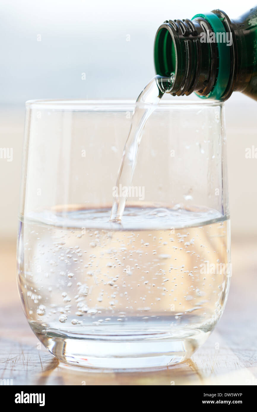 spring water pouring into glass from green bottle Stock Photo - Alamy