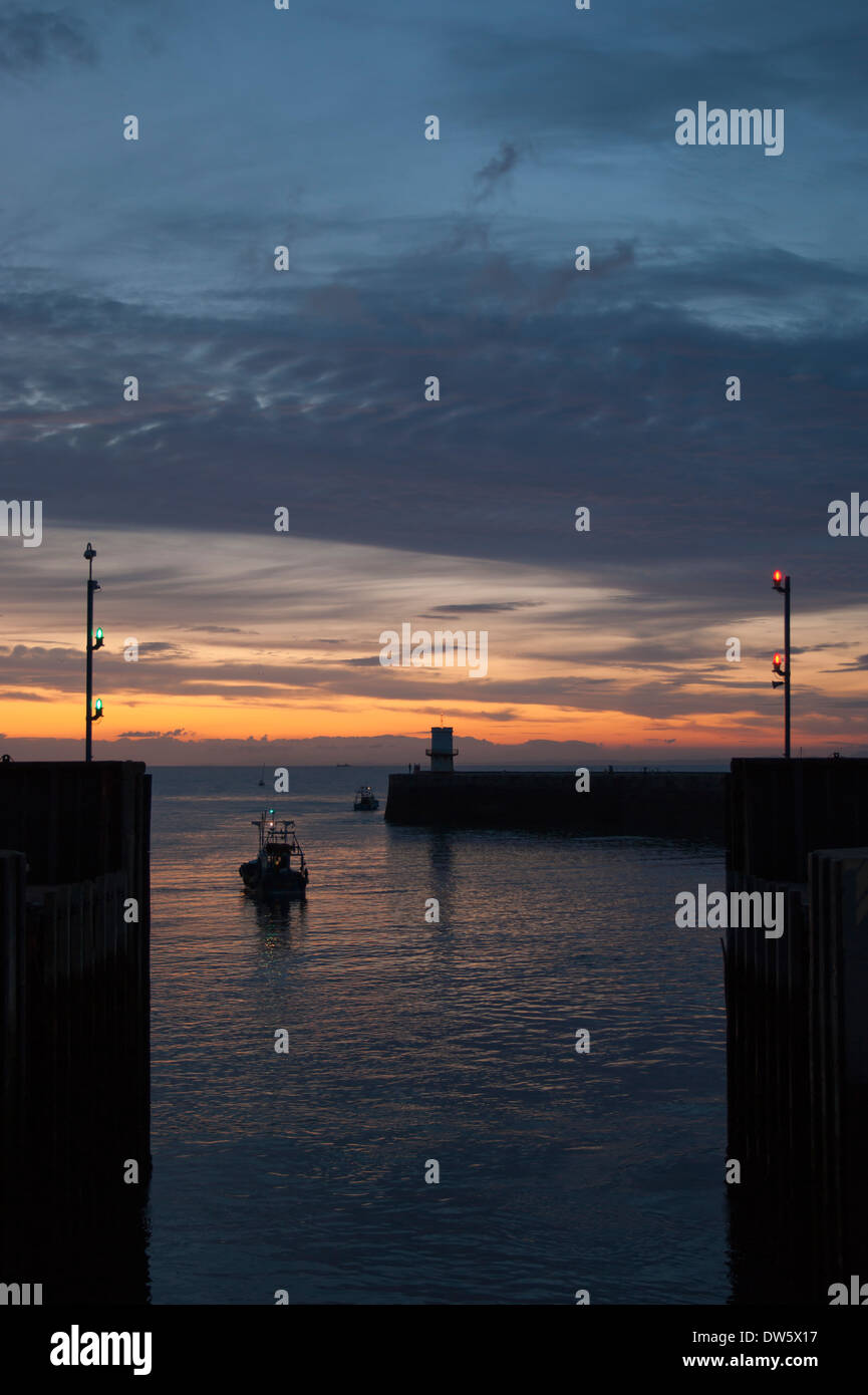A boat presenting itself to the harbour lock gates at dusk in ...
