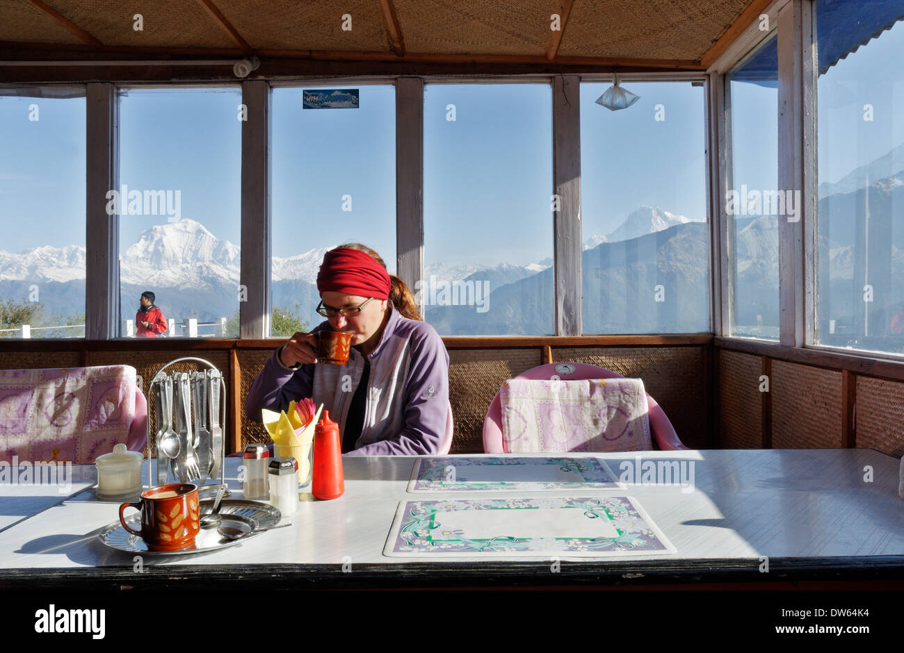 A lady trekker drinking tea in a tea house on the Annapurna circuit ...