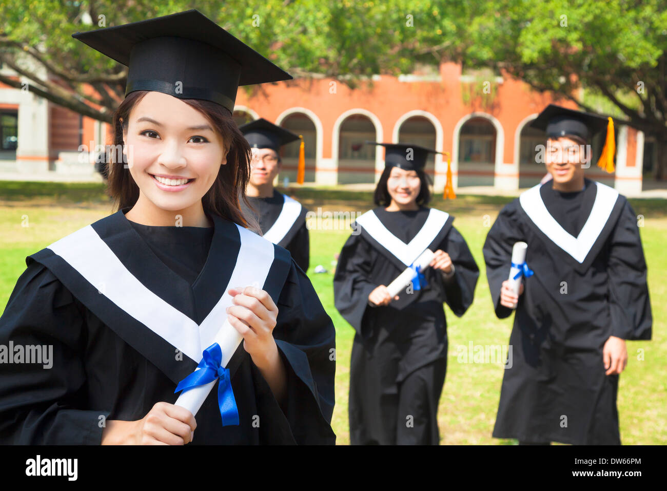 pretty asian college graduate holds a diploma with classmates Stock ...