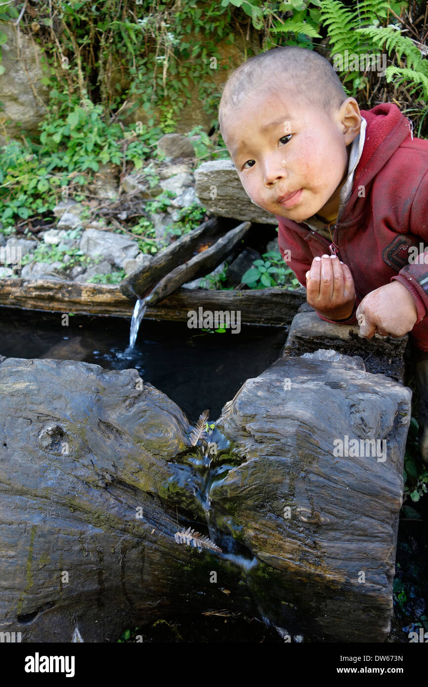 Nepalese boy drinking water from a spring in the Manaslu region of ...