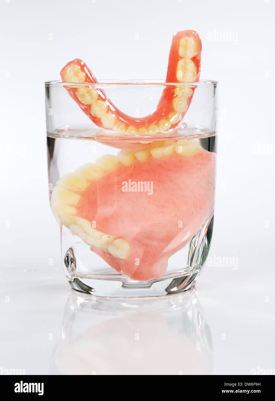 A set of dentures in a glass of water on a white background Stock Photo ...