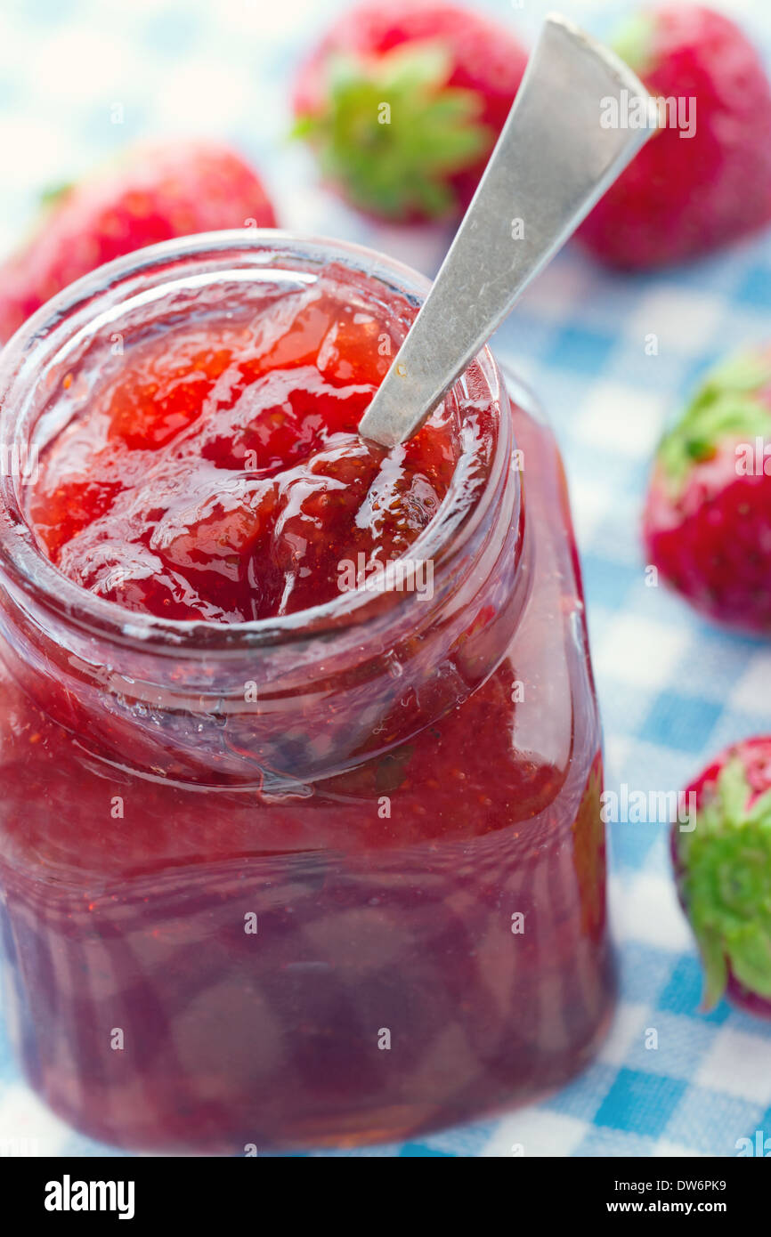 Jar of strawberry jam in a glass jar and fresh strawberries on blue ...