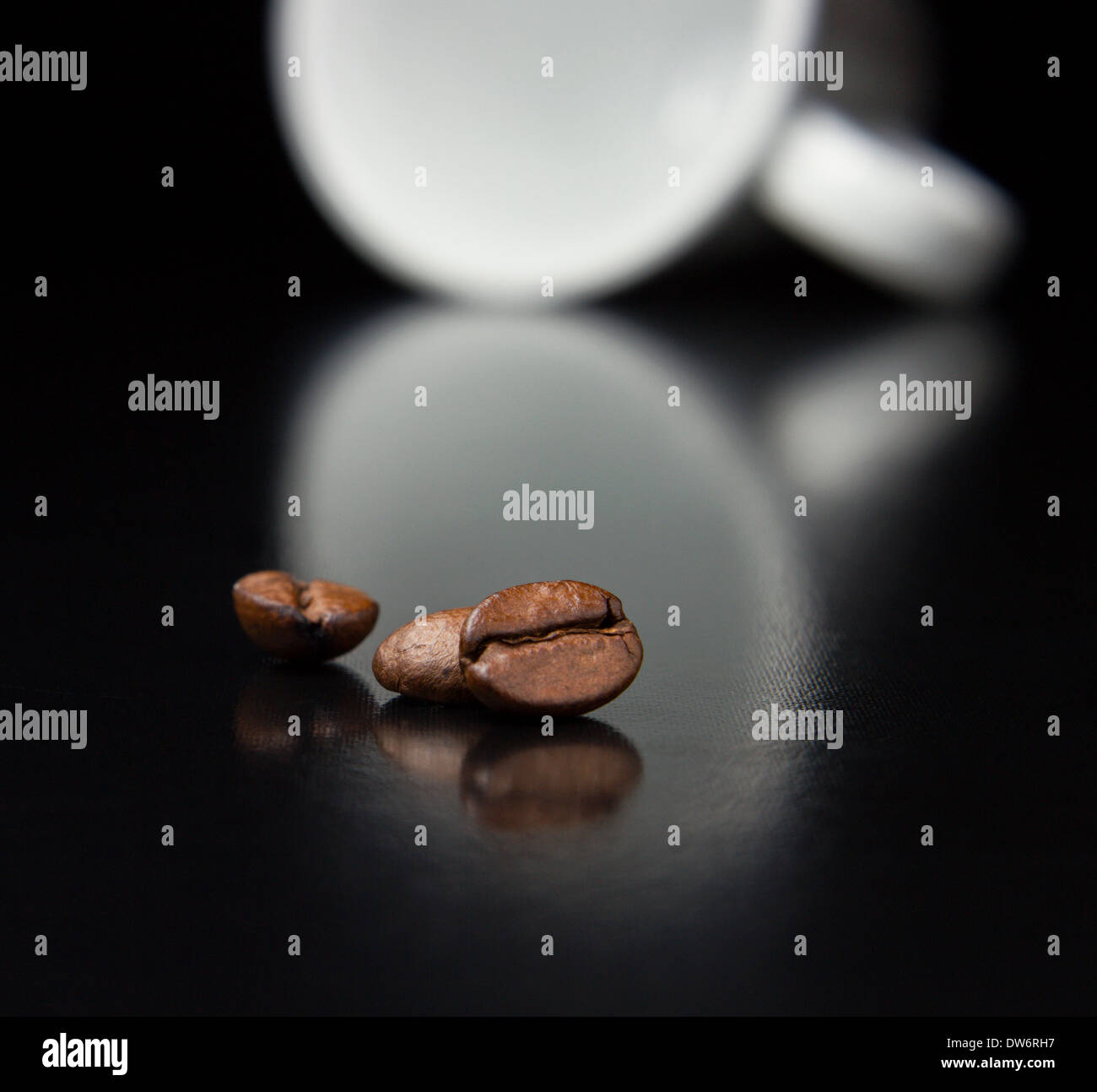 roasted coffee beans on dark table with fallen cup Stock Photo - Alamy