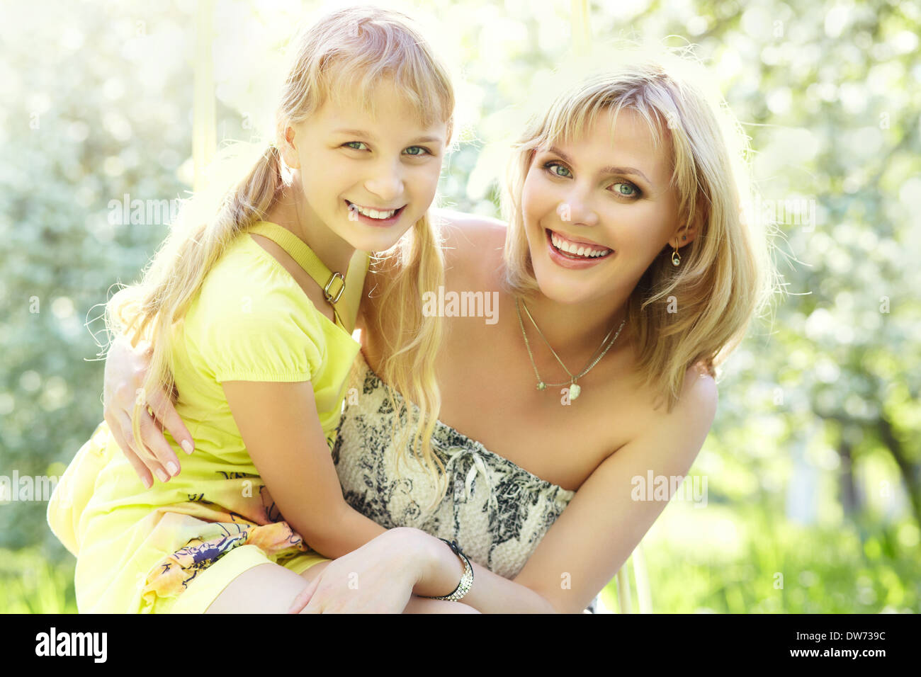 hugging happy mother and daughter for a walk in the park on a light green background Stock Photo ...