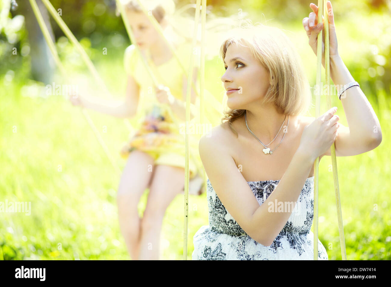 happy mother and daughter swinging on a swing for a walk in the park on a light green background ...