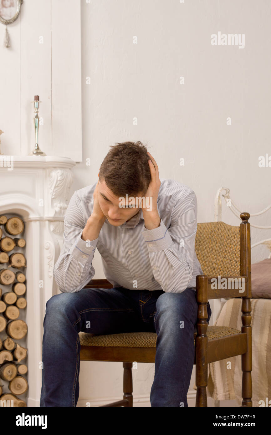 Young man sitting thinking in the living room Stock Photo - Alamy