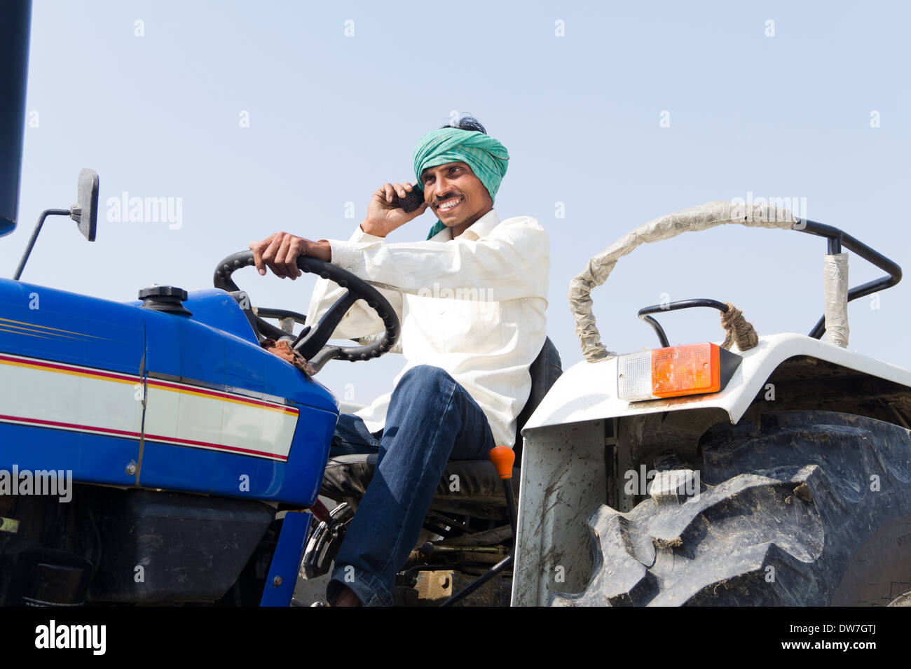 1 indian farmer driving tractor and talking Stock Photo - Alamy