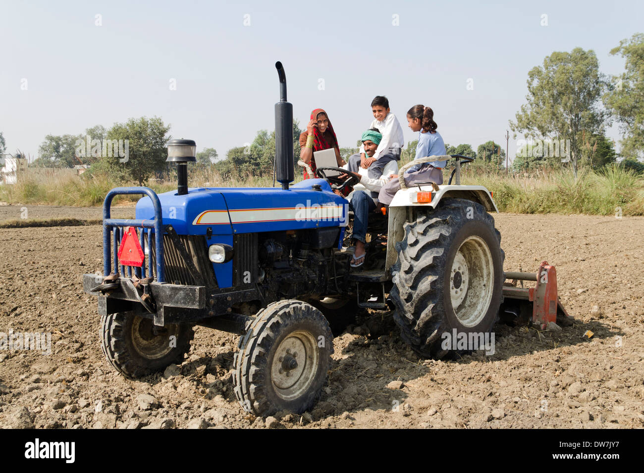 Indian farmer driving tractor with family and talking Stock Photo - Alamy