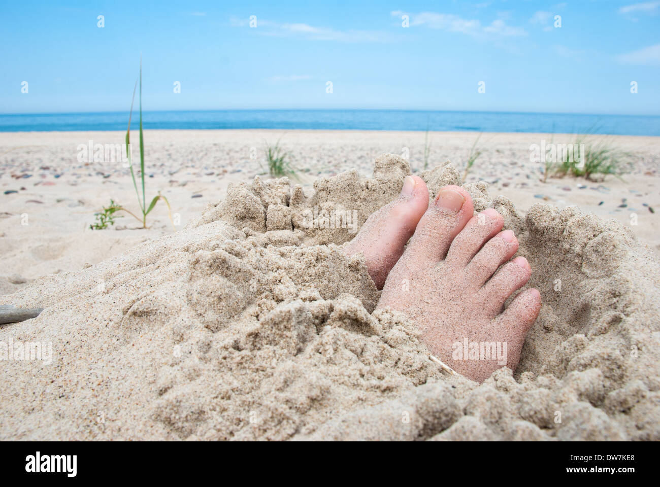 Feet buried in sand with uncovered toes on a beach Stock Photo - Alamy