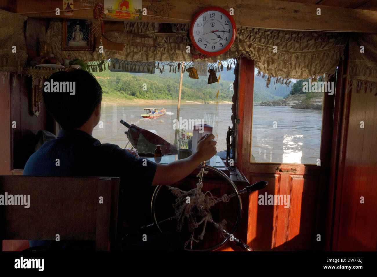 Captain steering a "slow boat" on the Mekong River in Laos Stock Photo ...