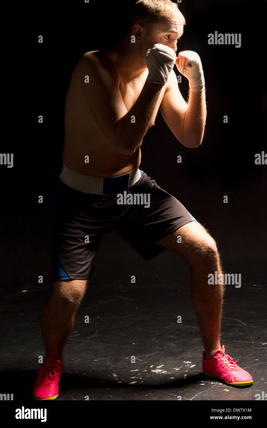 Determined young boxer during a fight squaring off to his opponent with ...