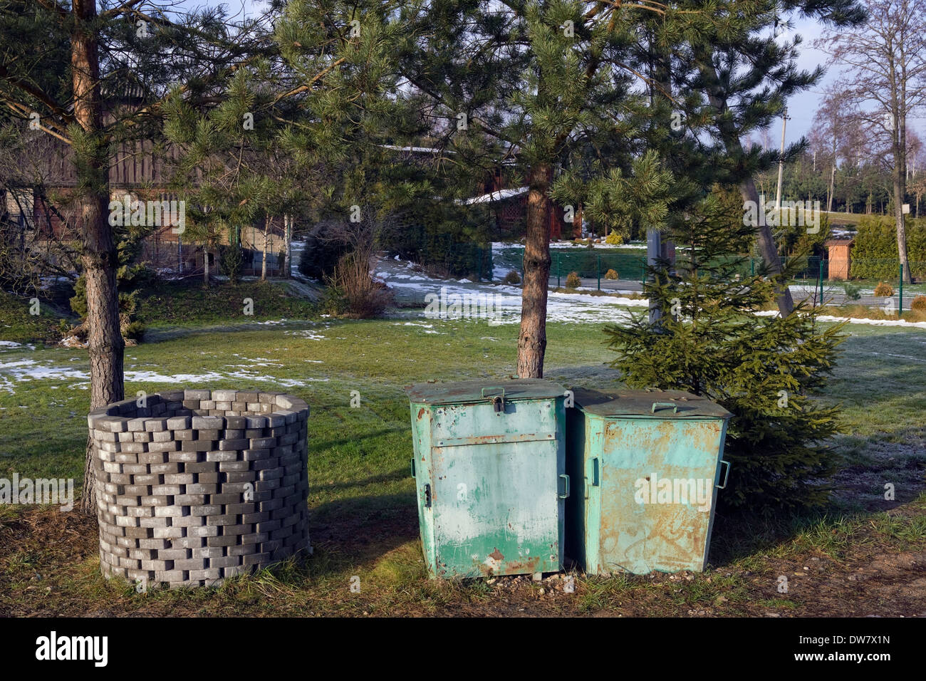 European rustic brick and tin trash cans are under pine trees. Sunny ...