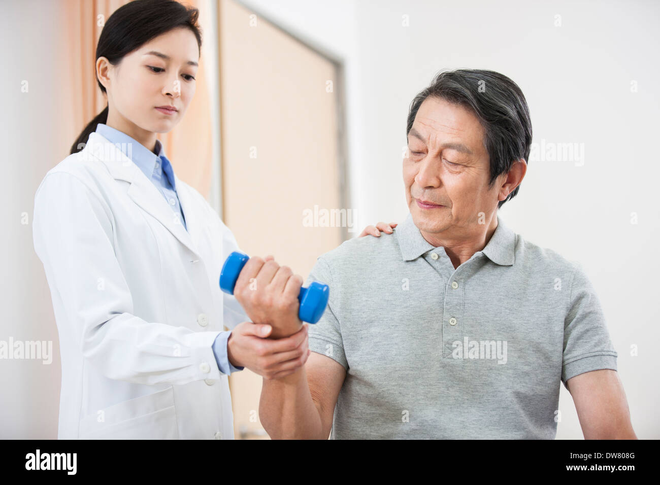 Senior patient exercising with dumbbell under doctor's help Stock Photo ...