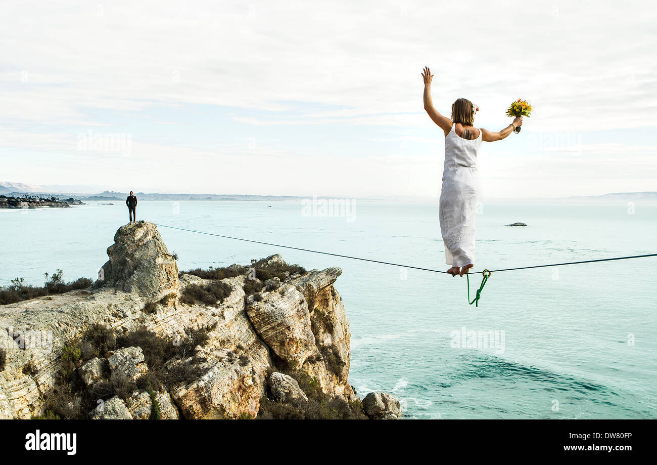 A woman in her wedding dress and holding flowers walks a 1-inch ...