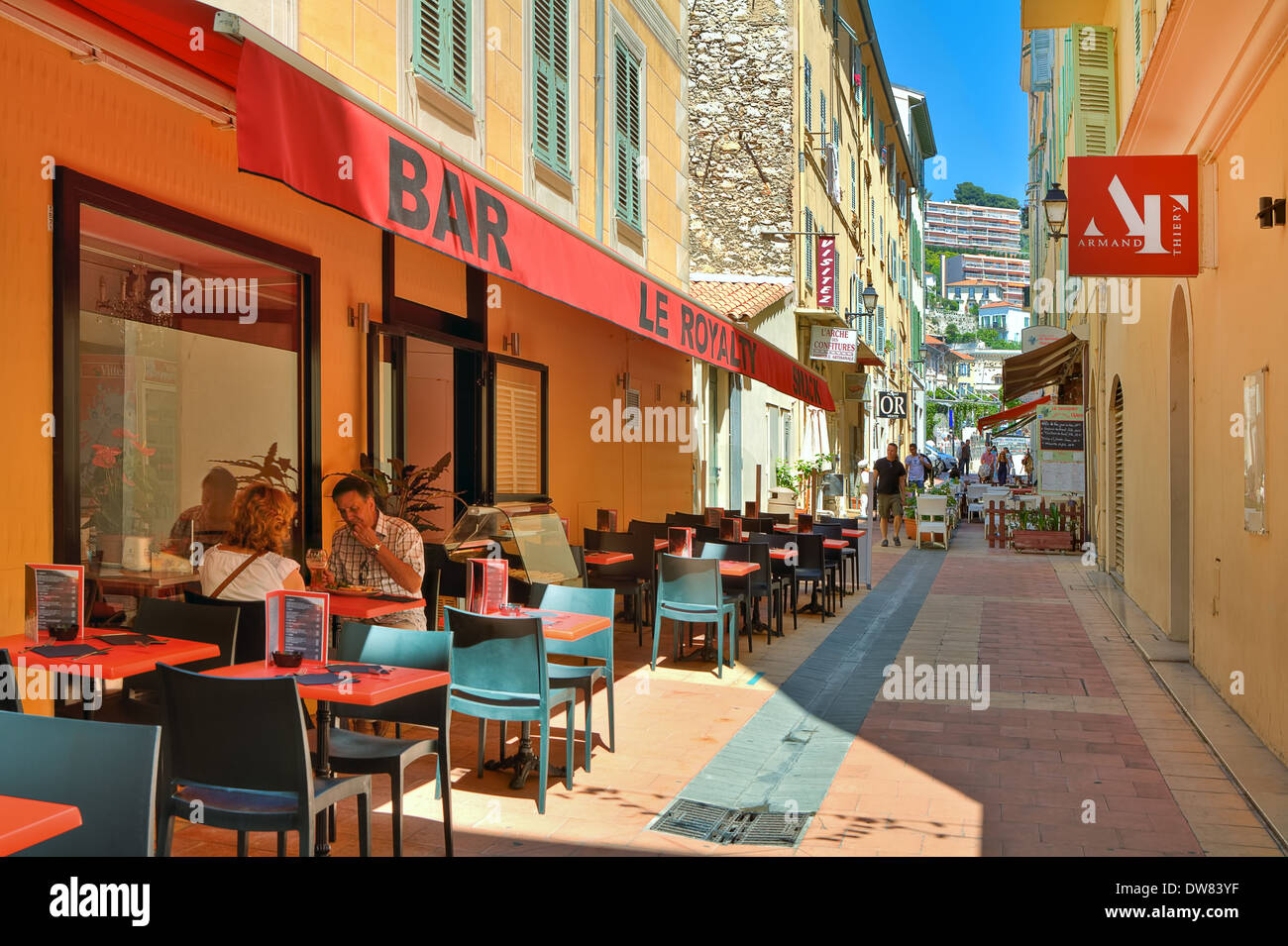 Bars, restaurants and shops on narrow street in old part of Menton ...