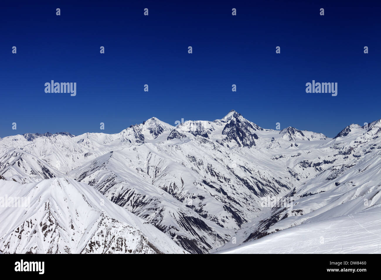 View on off-piste slope, winter snowy mountains and blue clear sky ...