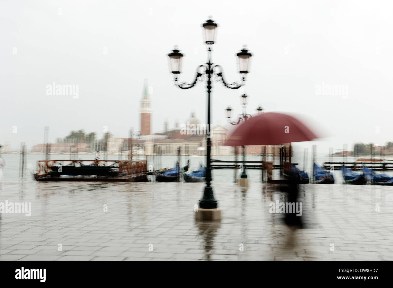 Italy, Venice, woman walking in rain on Riva degli Schiavoni looking ...