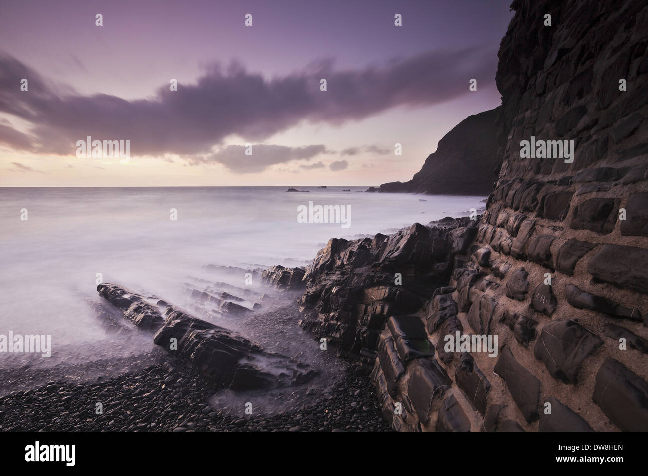 View of seawall rocks on beach and cliff at sunset Welcome Beach North ...