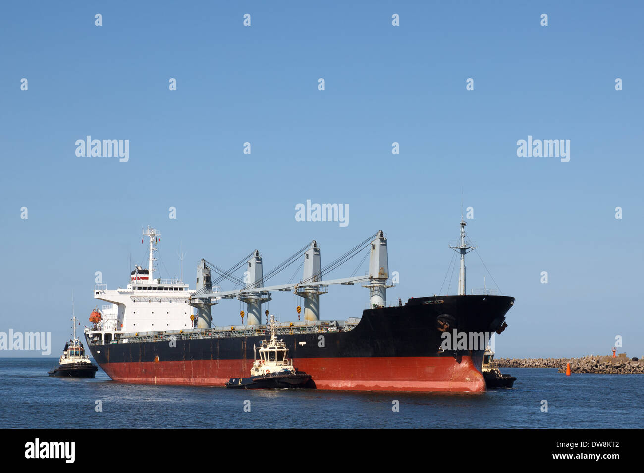 three tug boats driving cargo ship over the sea gate Stock Photo - Alamy