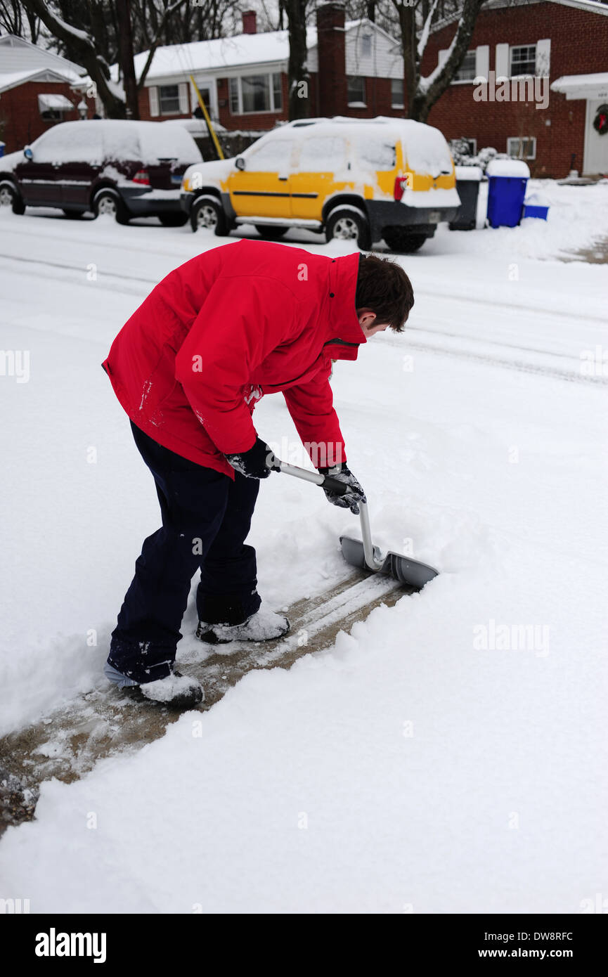 Man shoveling snow with a back saver shovel at a home driveway ...