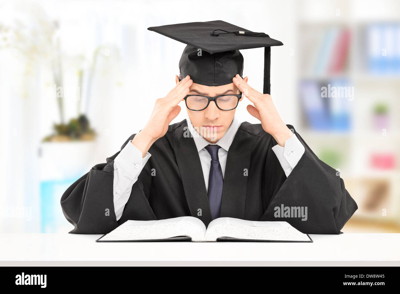Male student in graduation gown studying in a classroom Stock Photo - Alamy