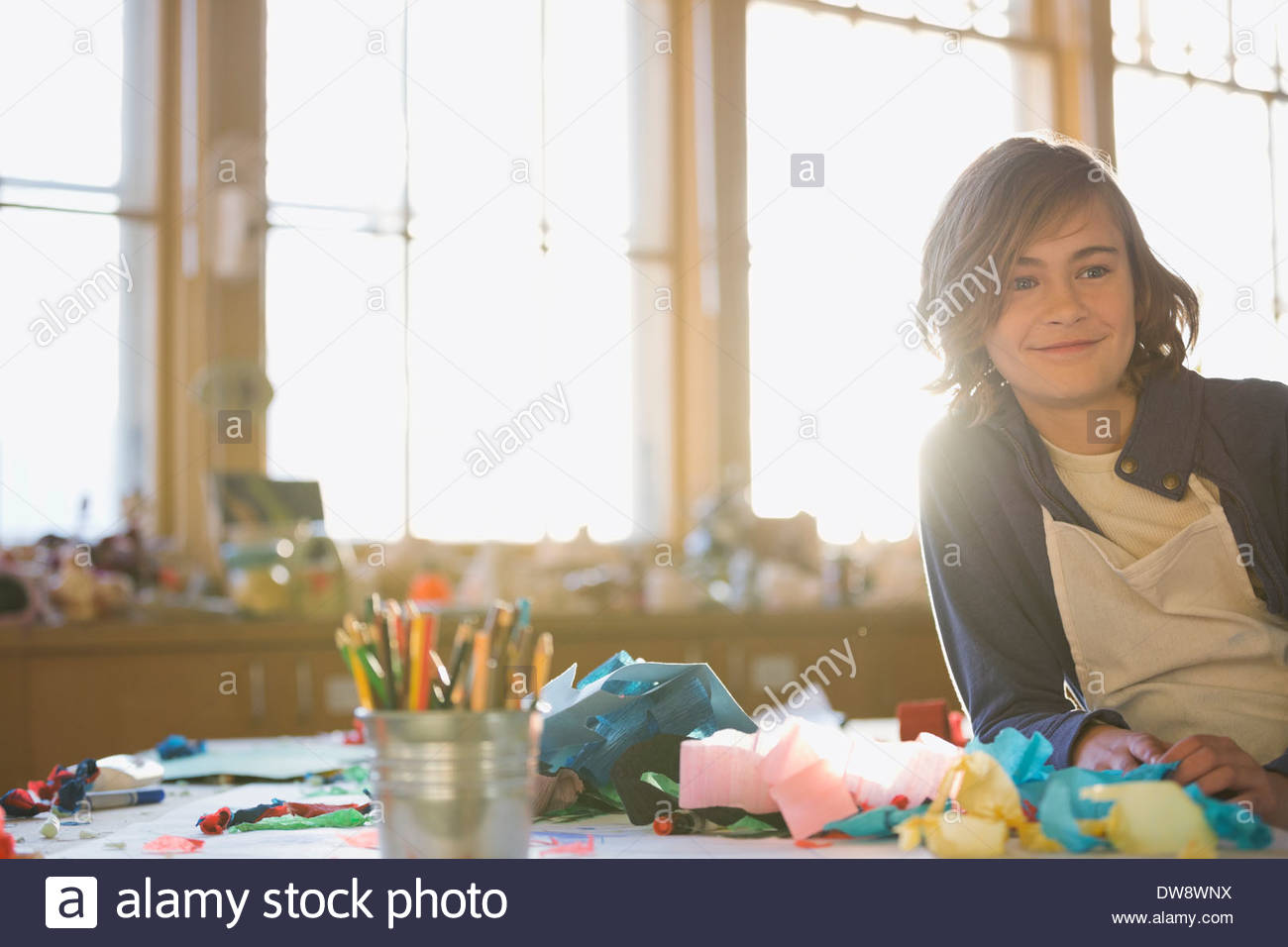 Boy leaning against table in art class Stock Photo - Alamy