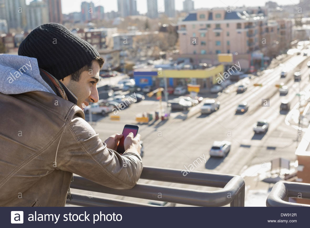 Man with smart phone leaning on patio railing Stock Photo - Alamy