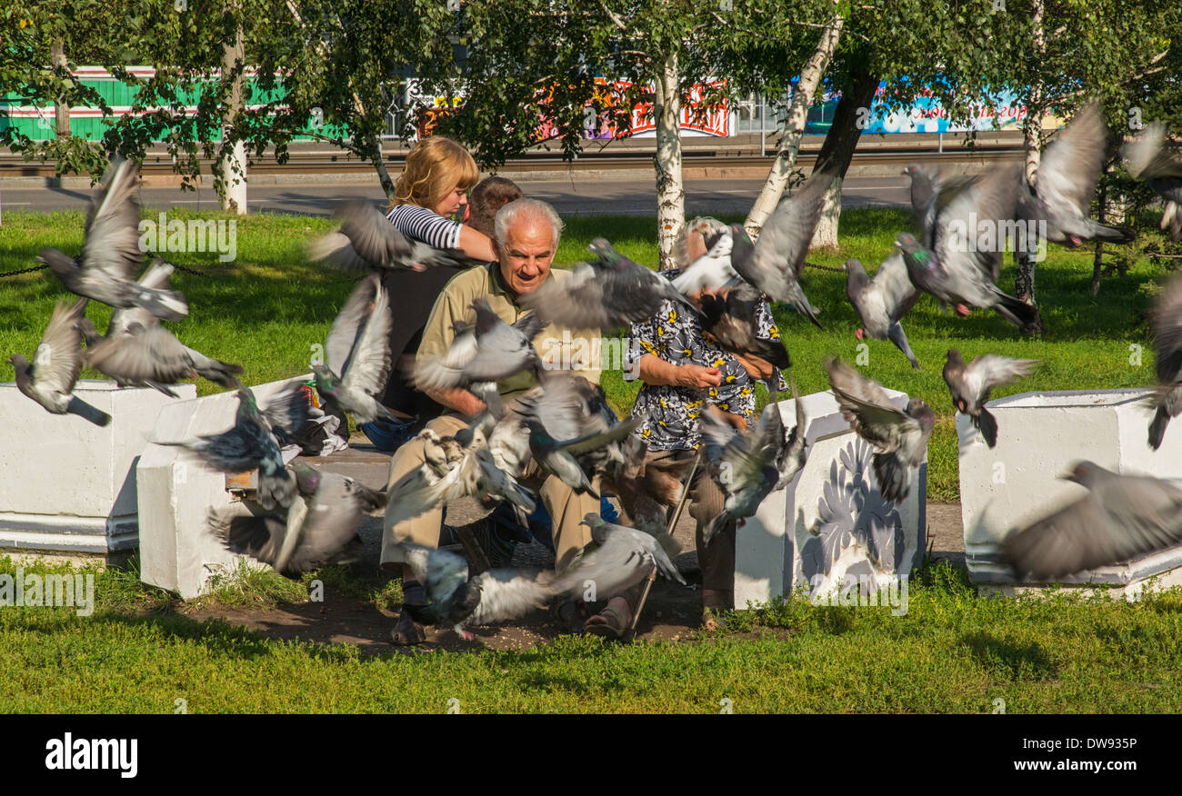 Doves flying in front of people sitting on the bench. Barnaul City ...