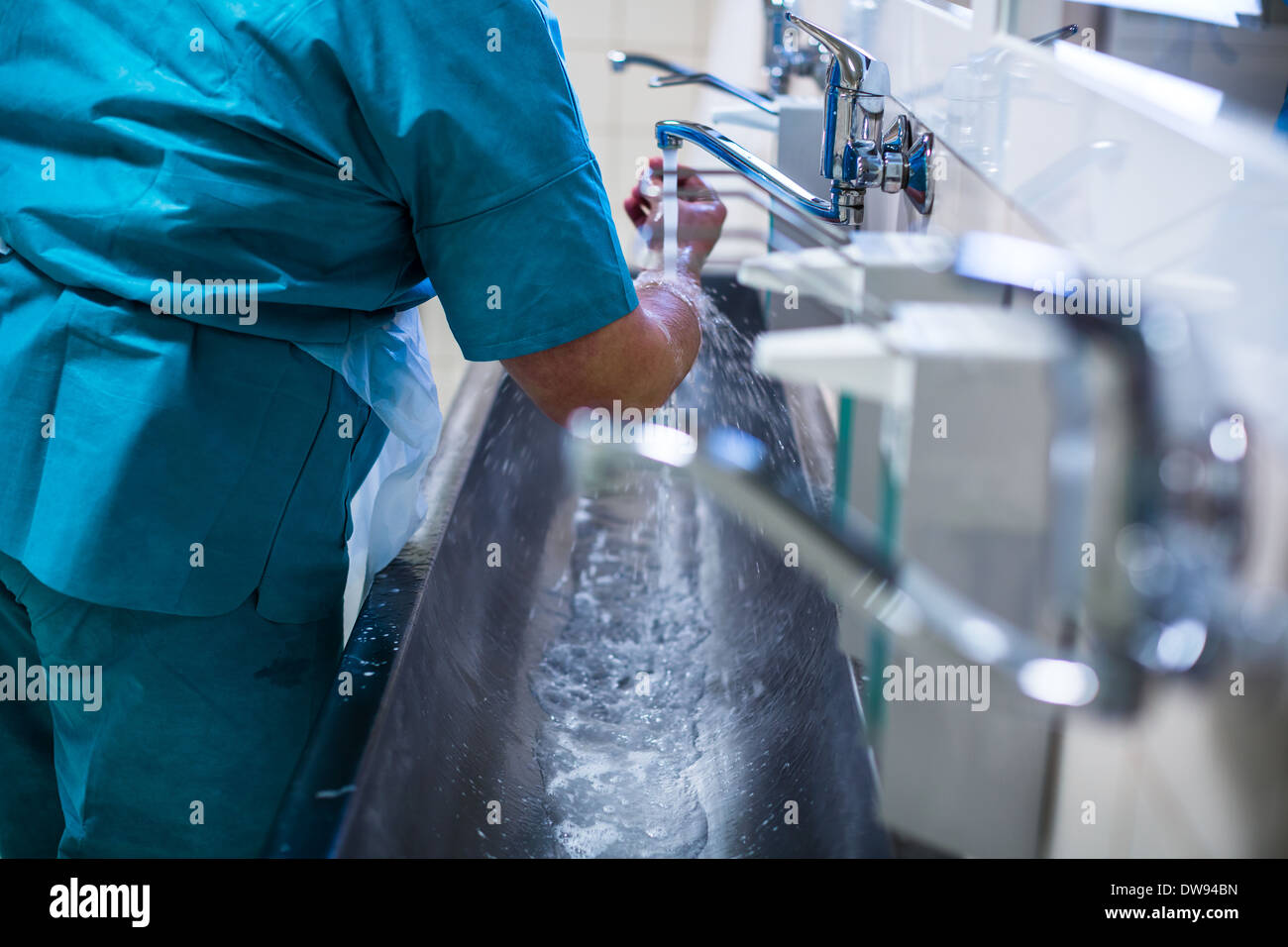 Surgeon in hospital washing thoroughly his hands before performing a ...