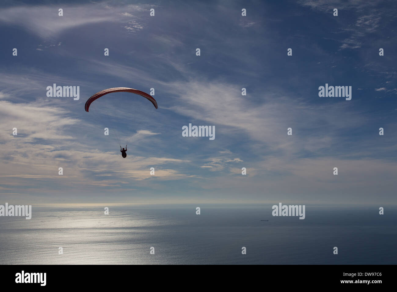 A paraglider against a backdrop of sky and ocean. In the abstract ...