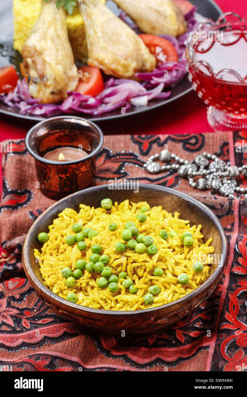 Indian cuisine, bowl of yellow rice with green peas on red background ...