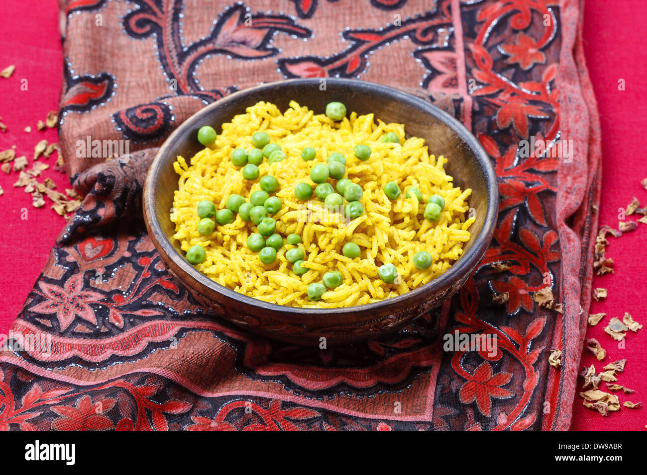 Indian cuisine, bowl of yellow rice with green peas on red background ...