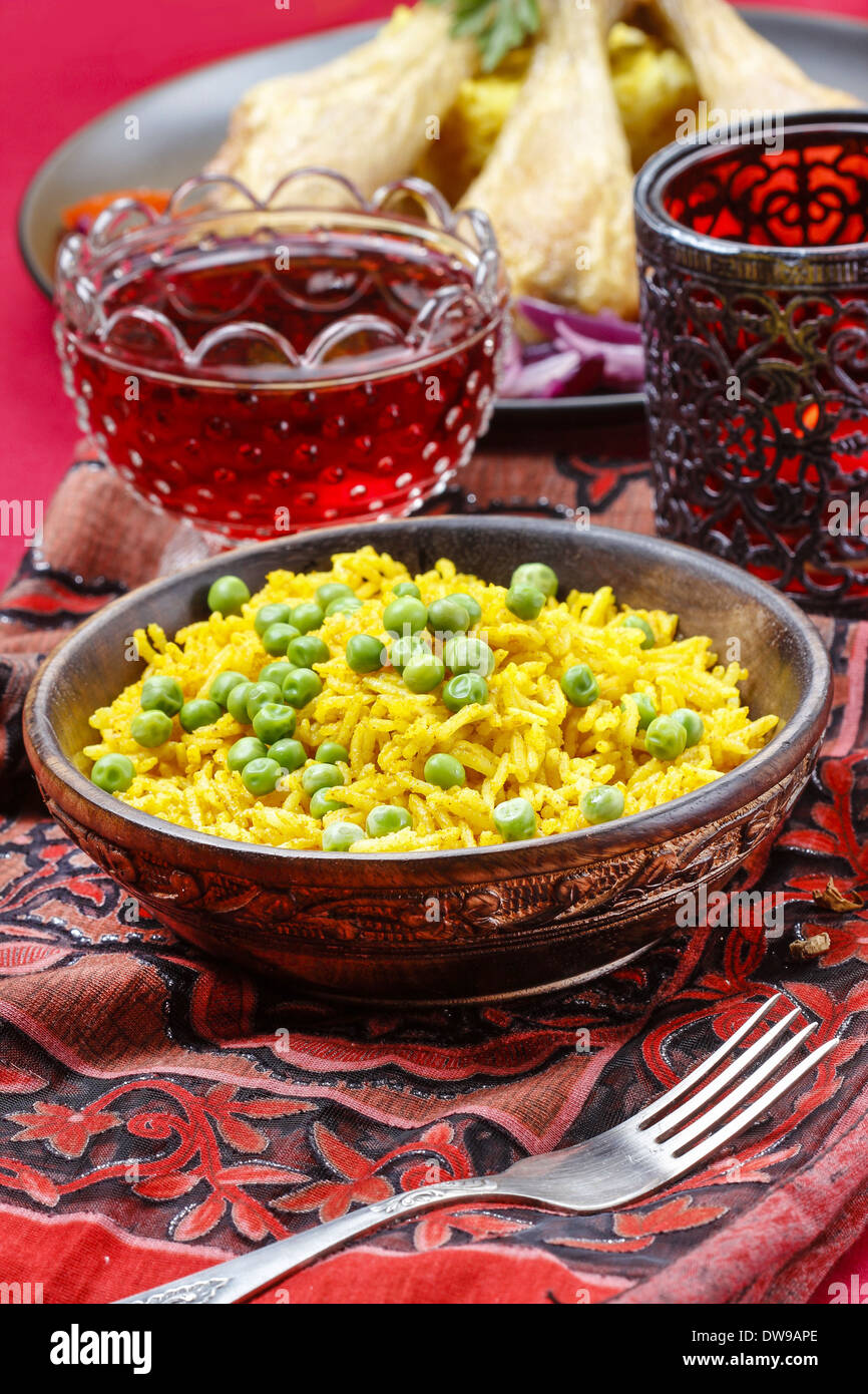 Indian cuisine, bowl of yellow rice with green peas on red background ...