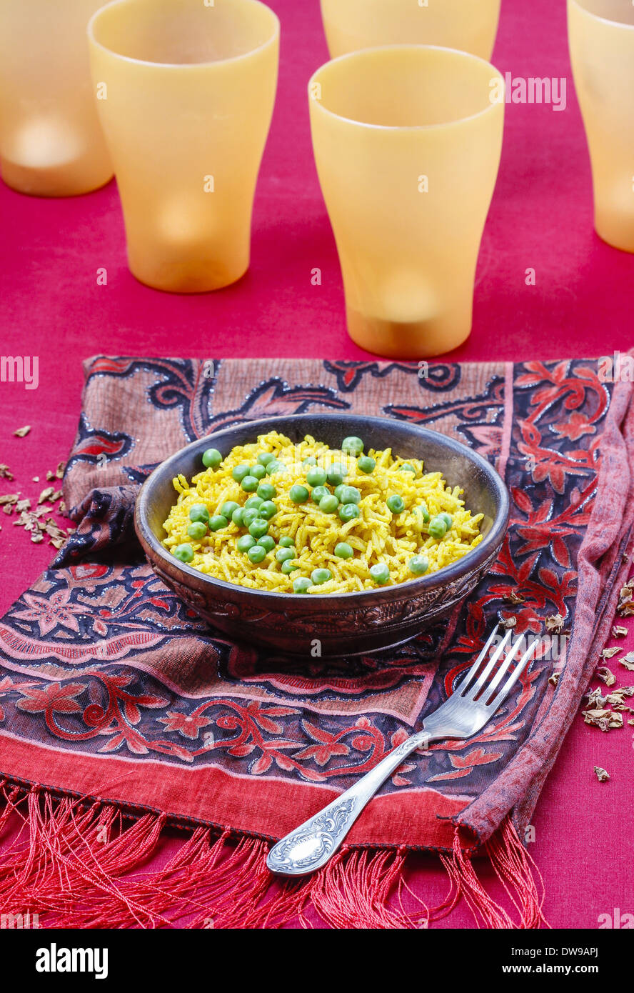Indian cuisine, bowl of yellow rice with green peas on red background ...