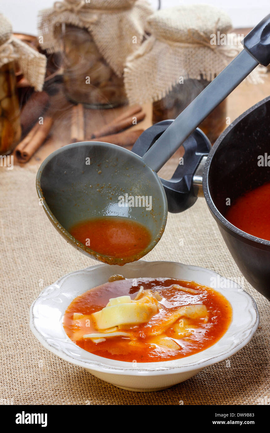 Serving tomato soup. Pouring soup into a plate Stock Photo - Alamy
