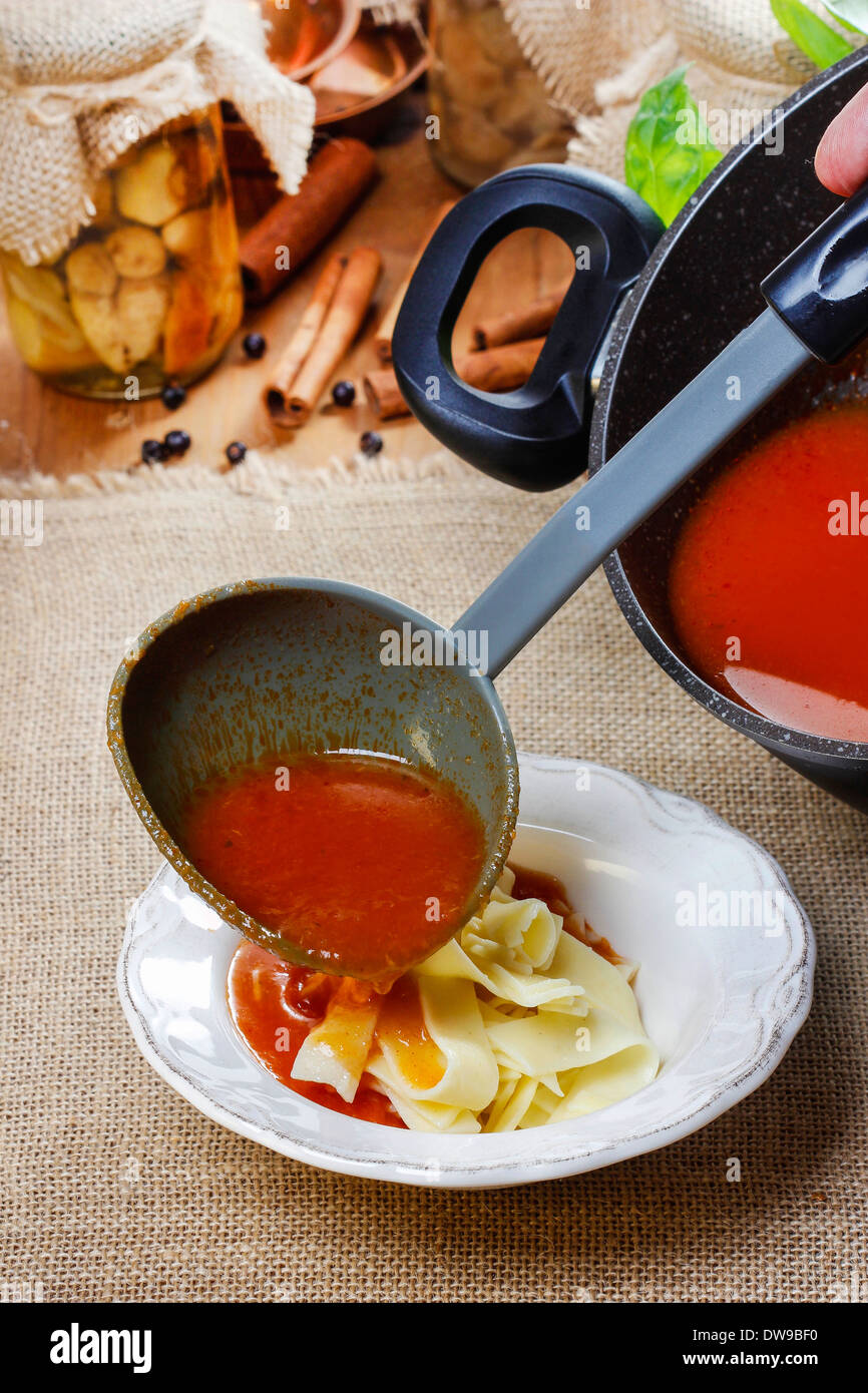 Serving tomato soup. Pouring soup into a plateServing tomato soup ...
