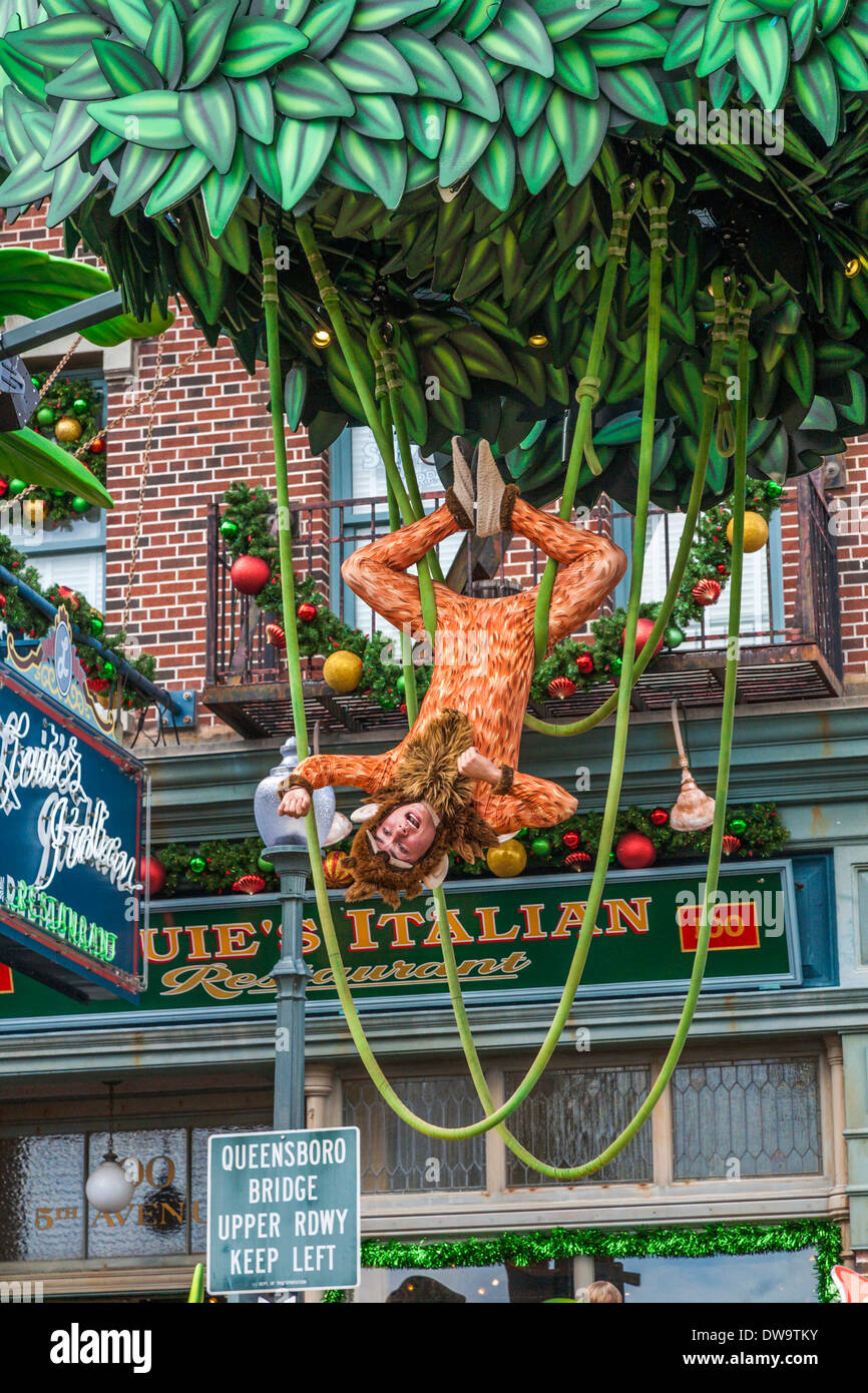 Young male acrobat in monkey costume hanging upside down on parade ...
