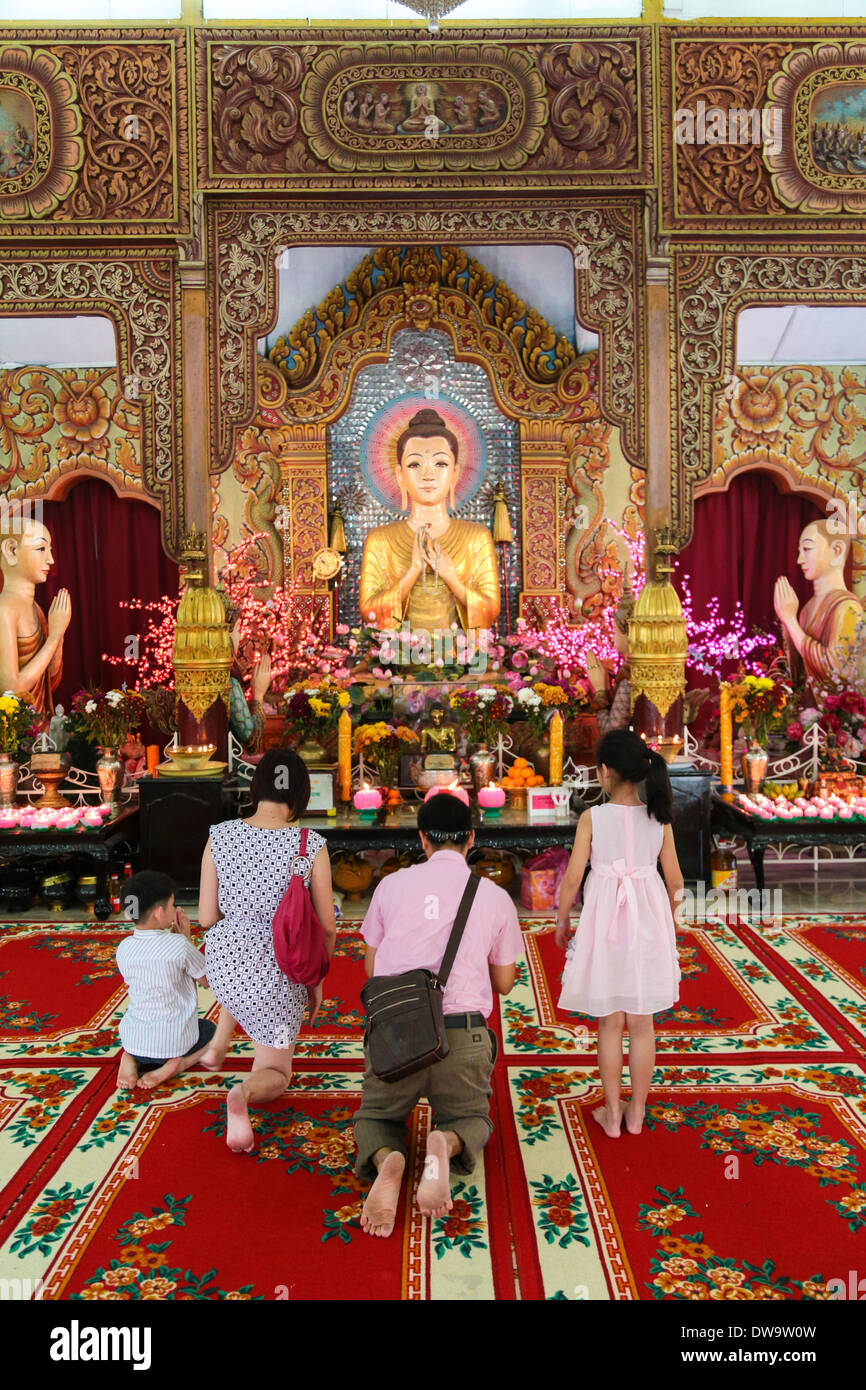 Family members praying inside the Dhammikarama, a burmese buddhist ...