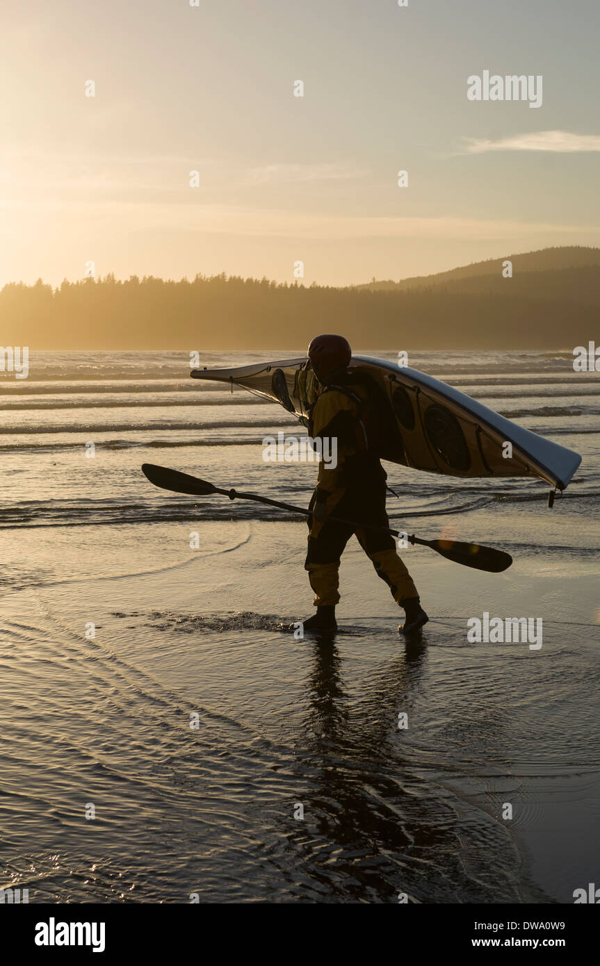 Man carrying kayak on beach at Bahobohosh Point, Makah Bay, Washington ...