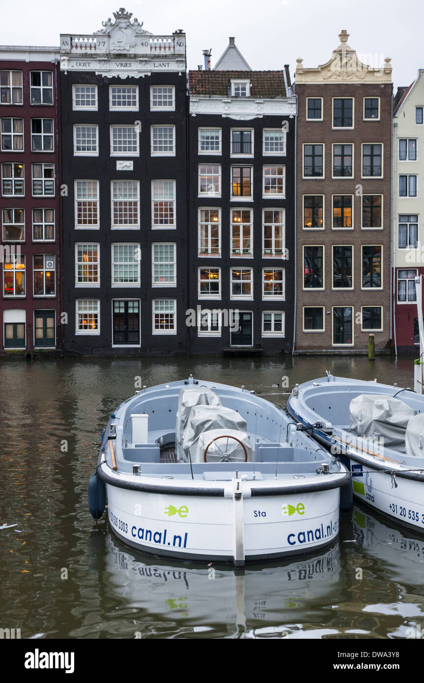 Tourist boats on the canal in front of traditional Dutch buildings ...