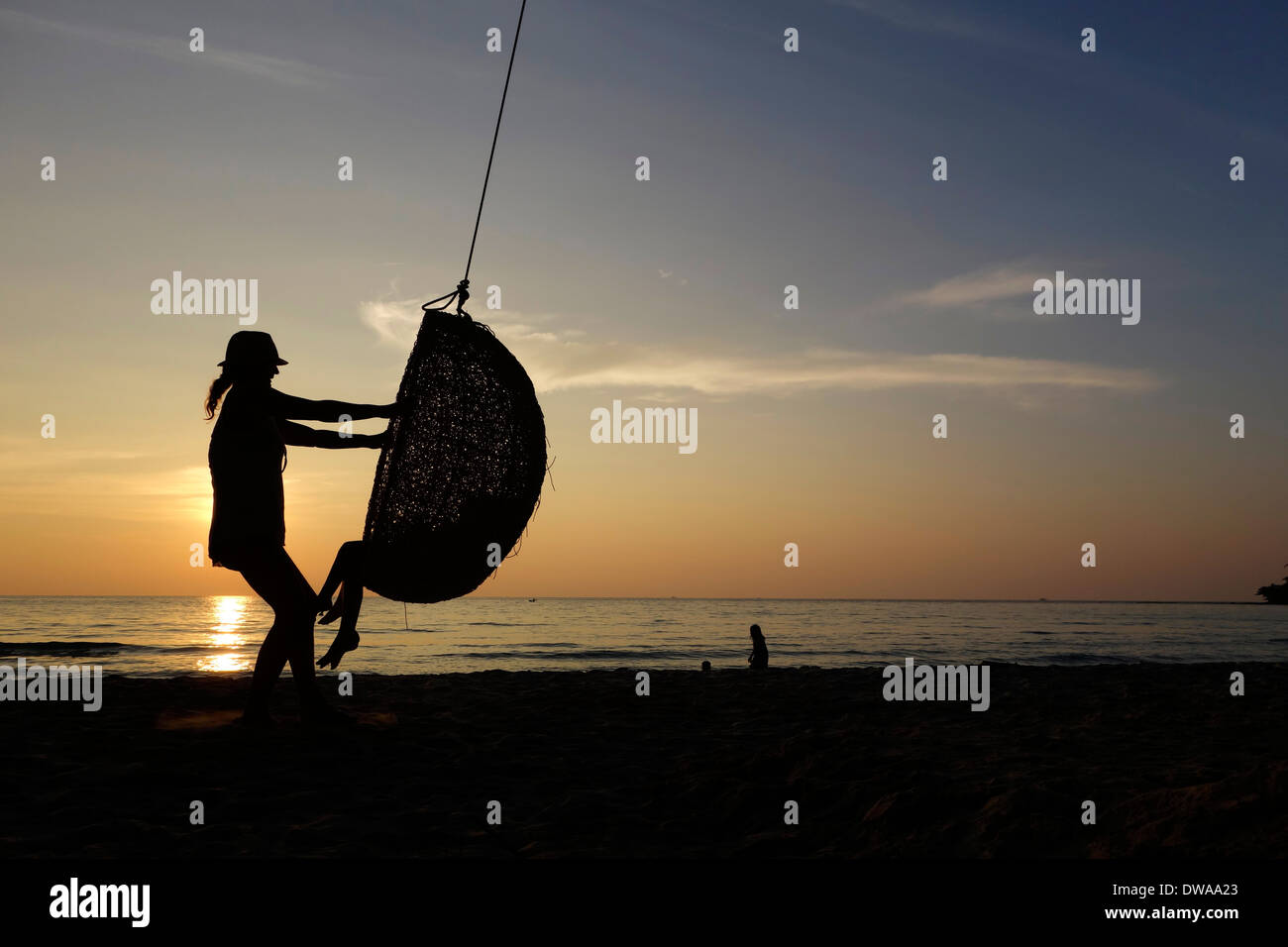 Playing in a rope swing at sunset on a beach on the island of Koh Kood ...