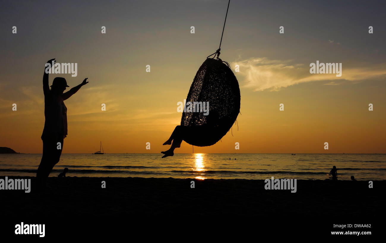 Playing in a rope swing at sunset on a beach on the island of Koh Kood ...