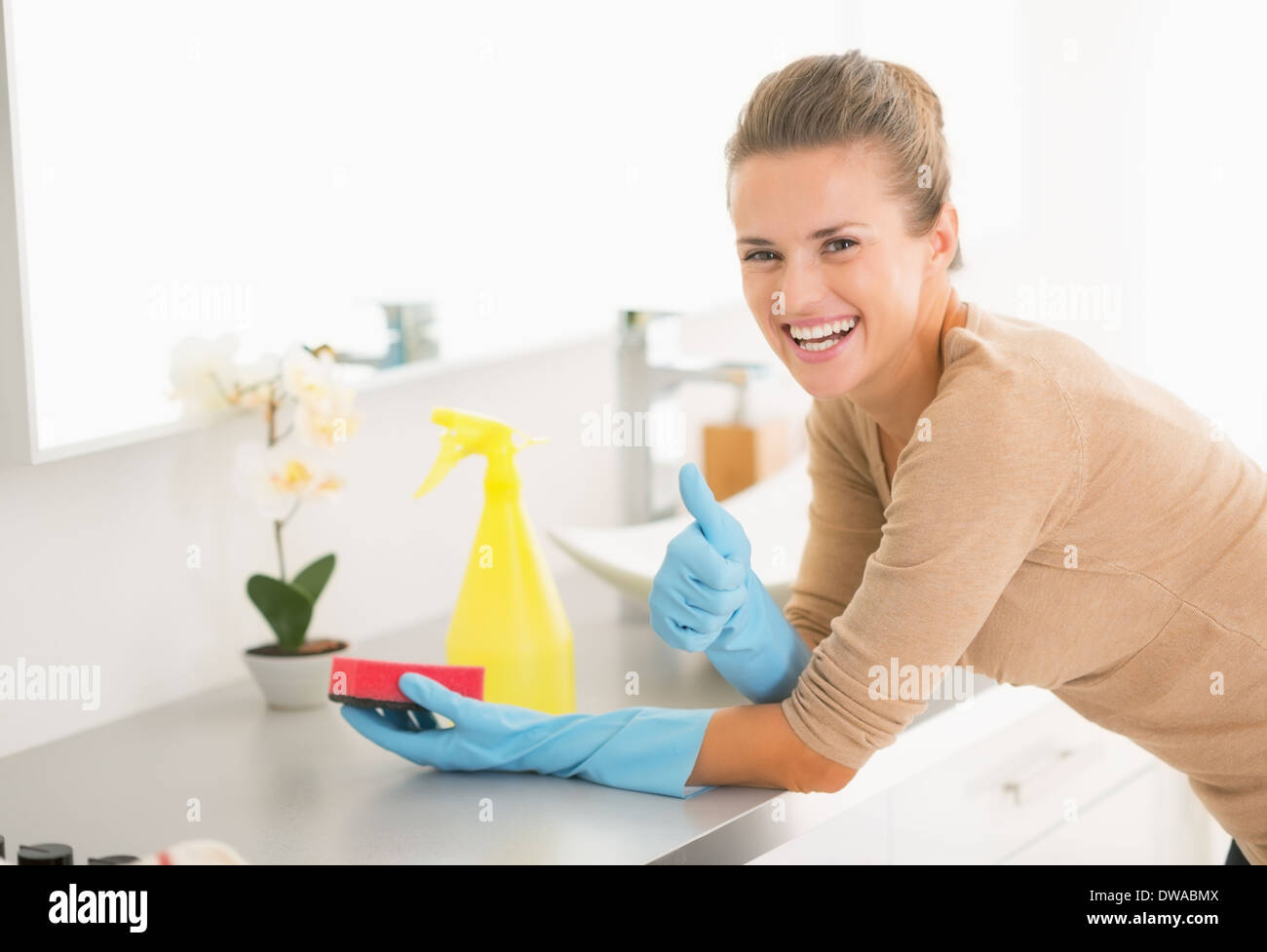 Portrait of happy young housewife showing thumbs up while cleaning ...