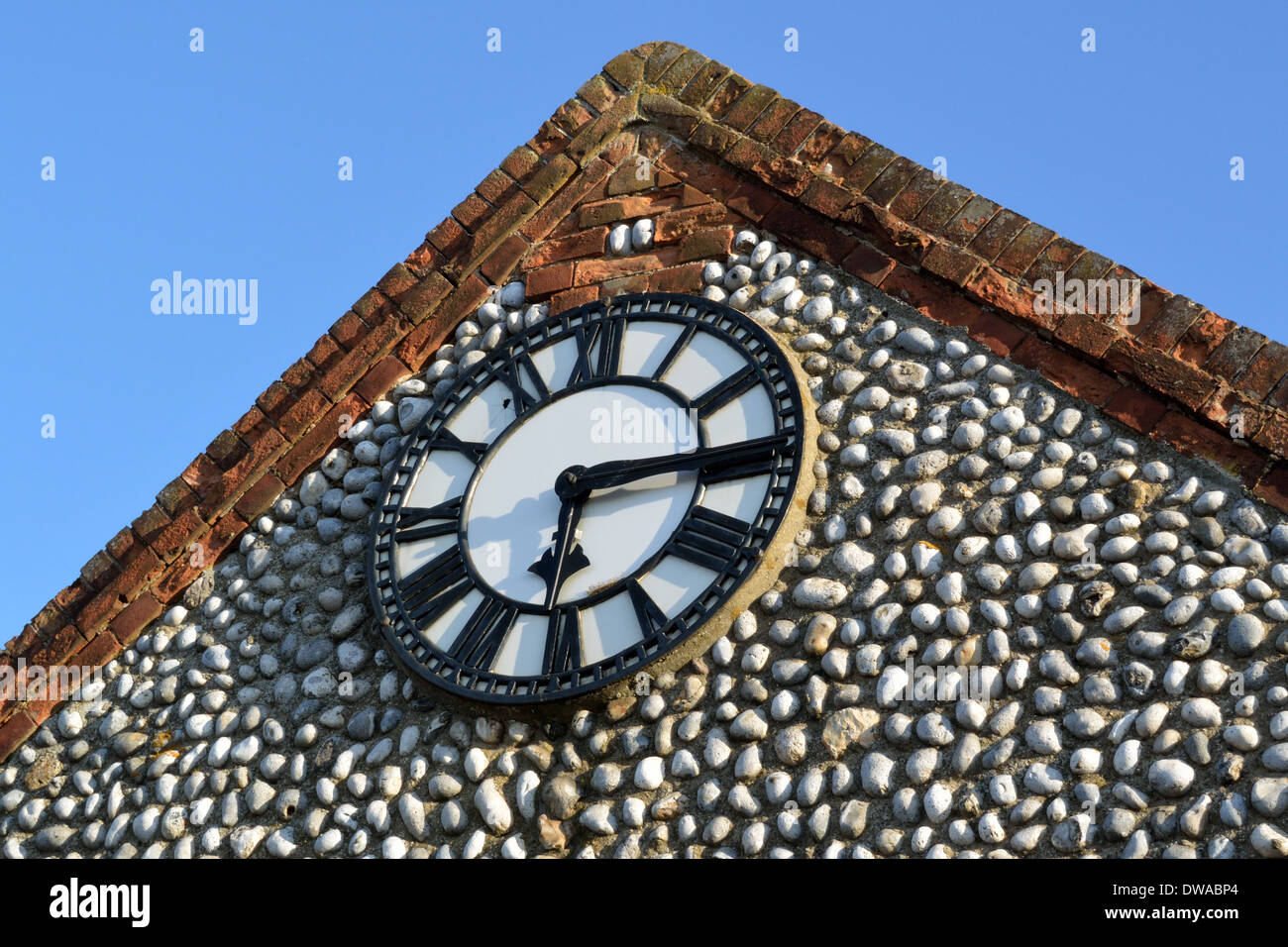 Traditional clock on flint and brick wall of St Nicholas church hall ...